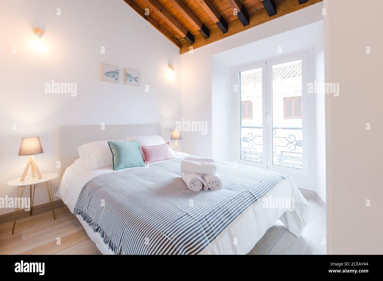 Comfortable light room with big bed and lamps near window in modern ...