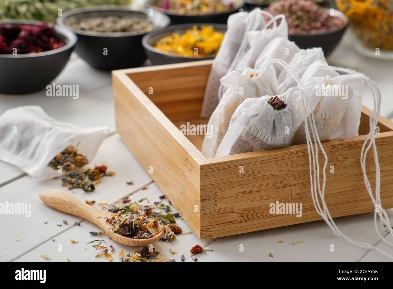 Wooden box of tea bags filled with dry medicinal herbs. Black bowls of ...
