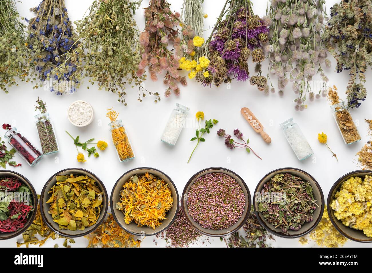 Bottles of homeopathic globules and dry medicinal plants. Bowls of dry ...