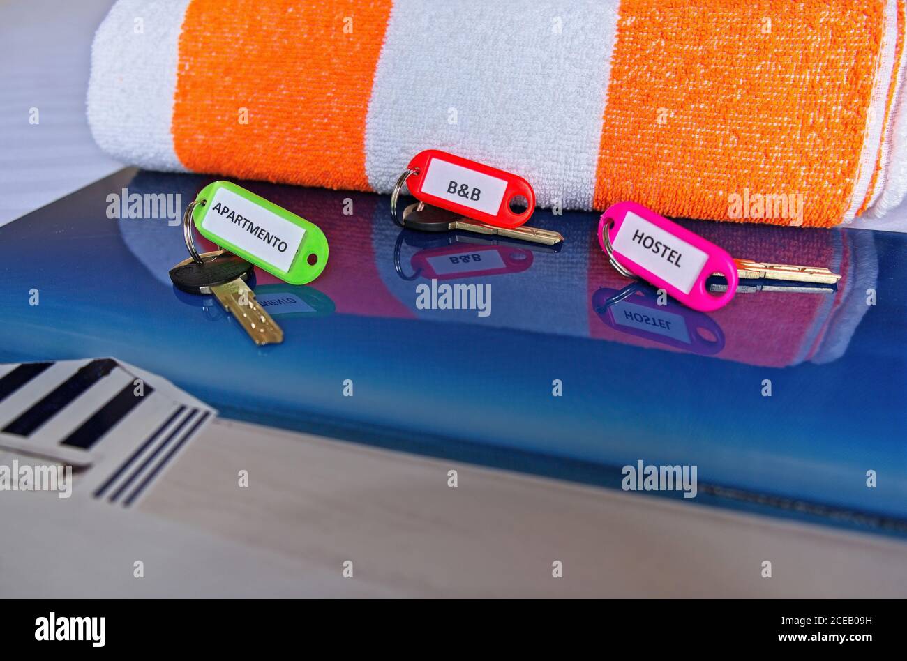 Three various hotel rooms keys with tags lying near rolled-up towel ...