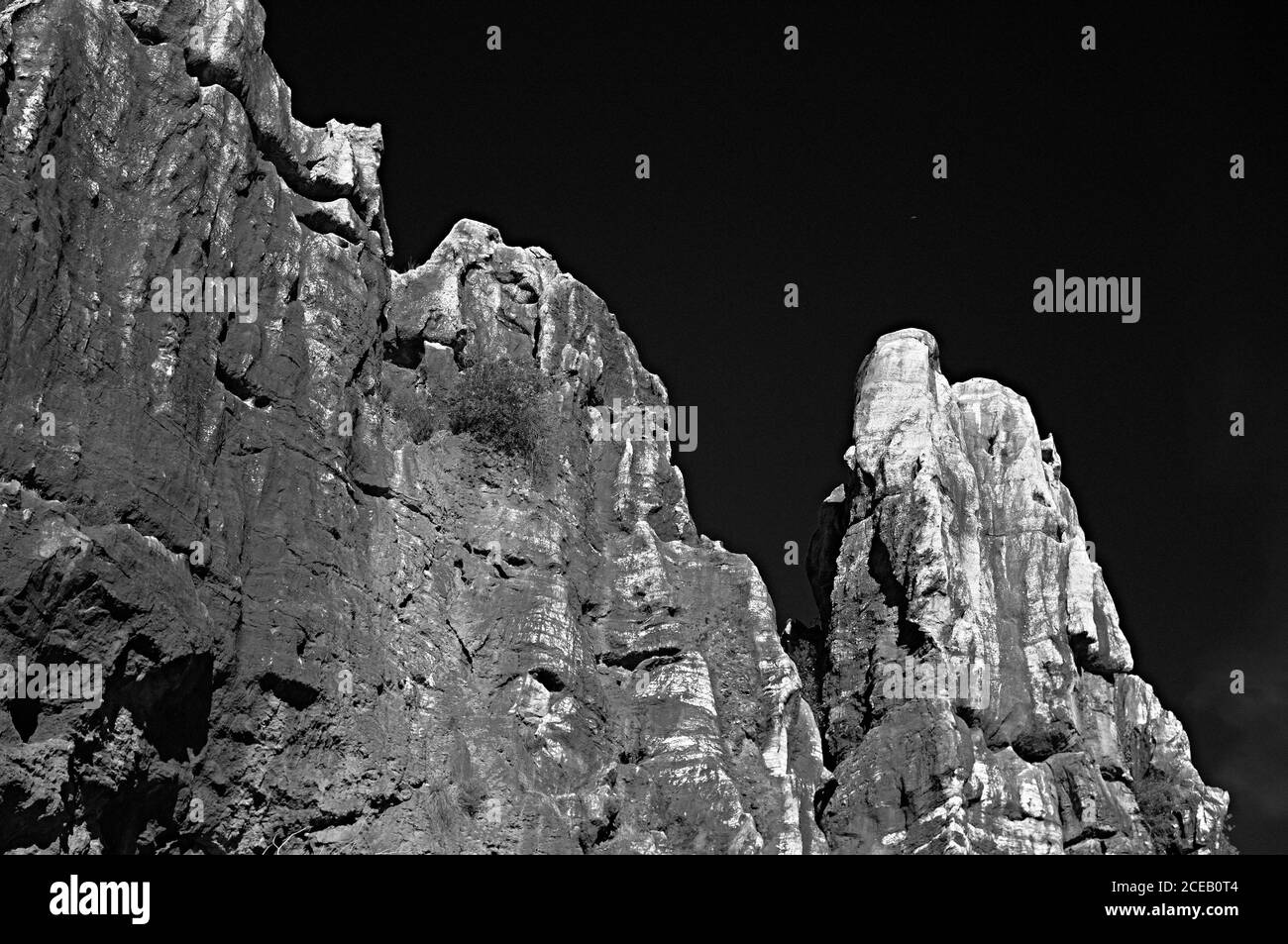 High steep sharp rocks with trees growing at bottom on background of ...