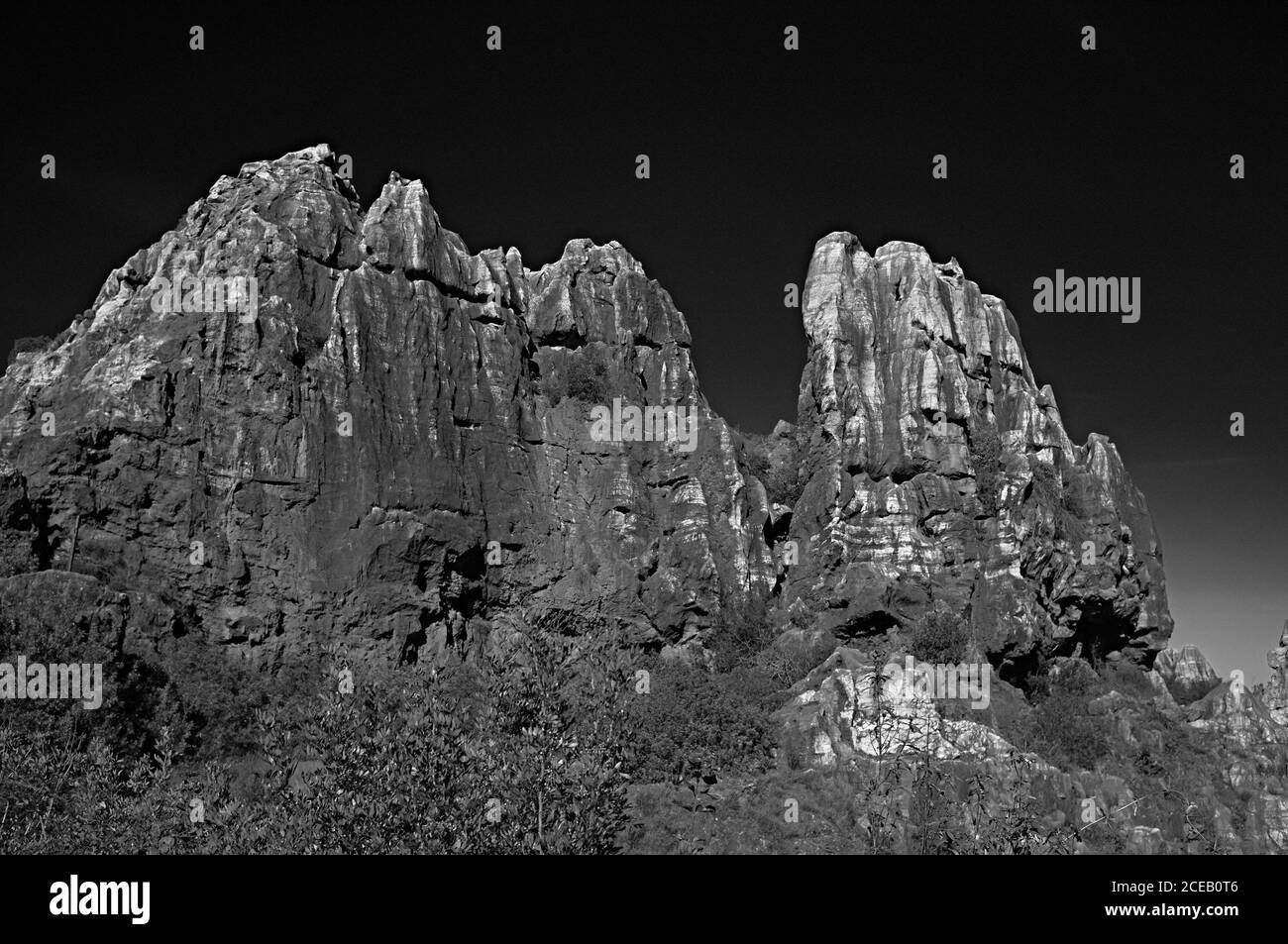 High steep sharp rocks with trees growing at bottom on background of ...