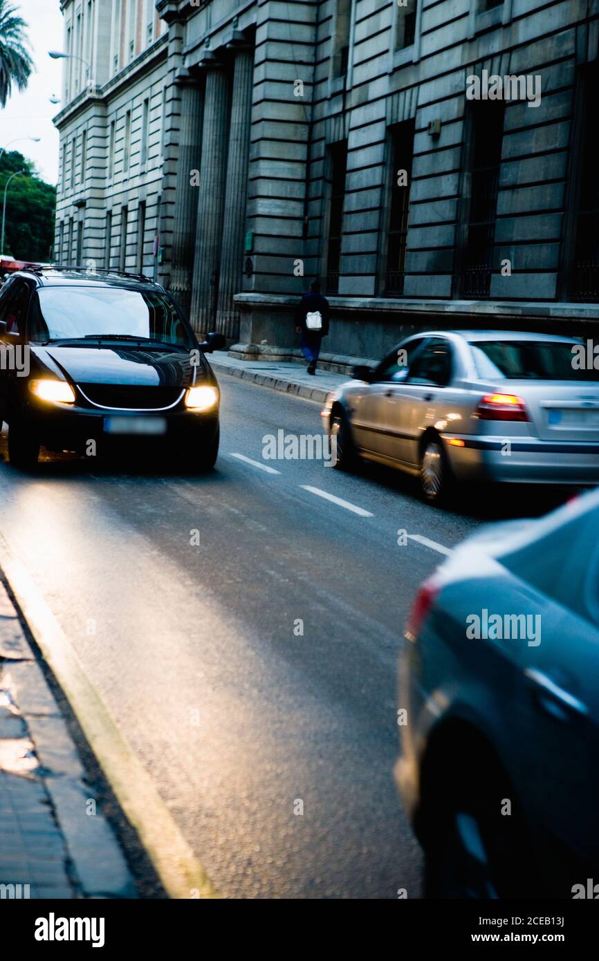 Blurred cars with glowing lights in motion driving on paved city road ...