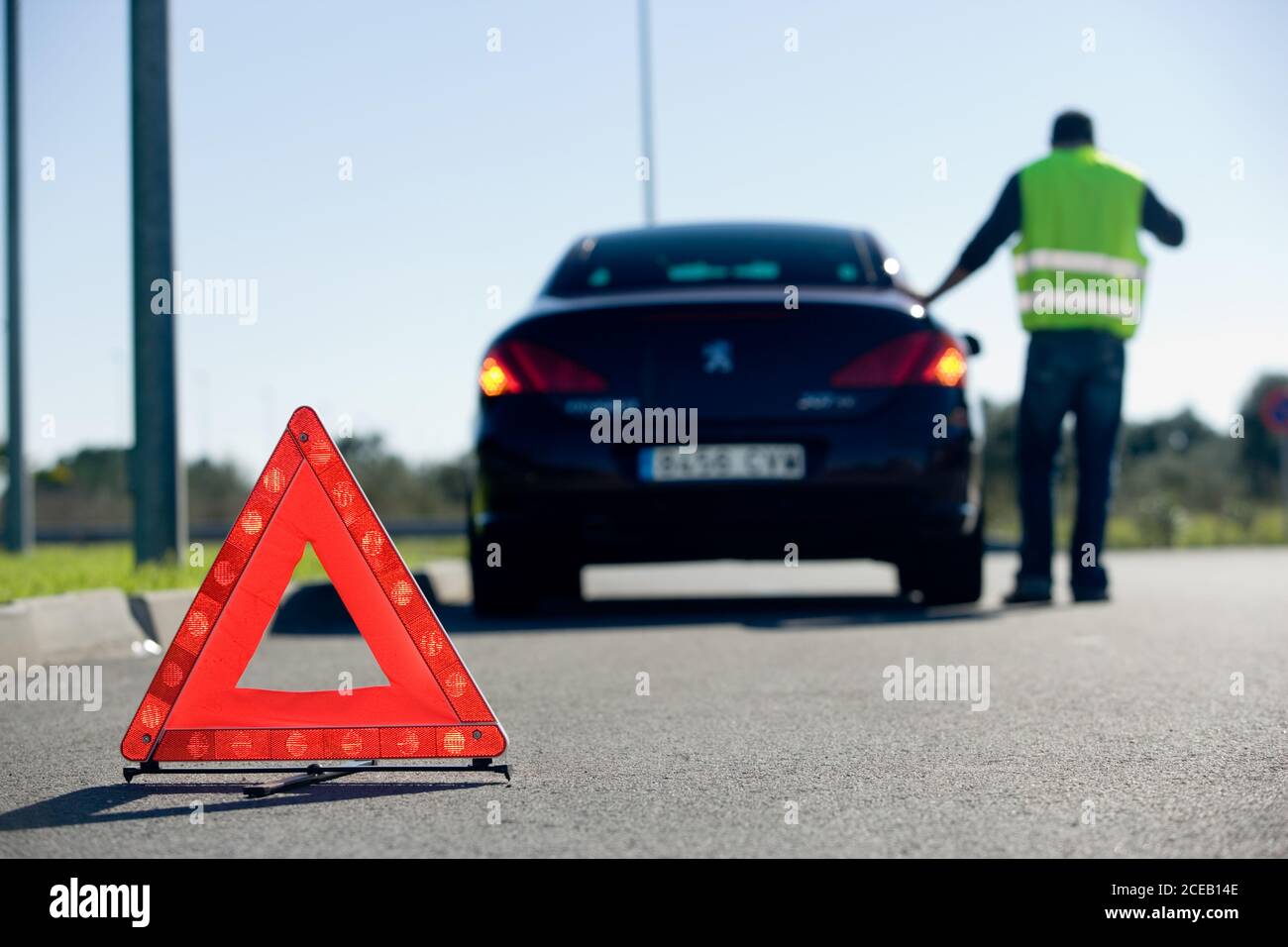 Warning red triangle sign on highway pavement with car on background ...