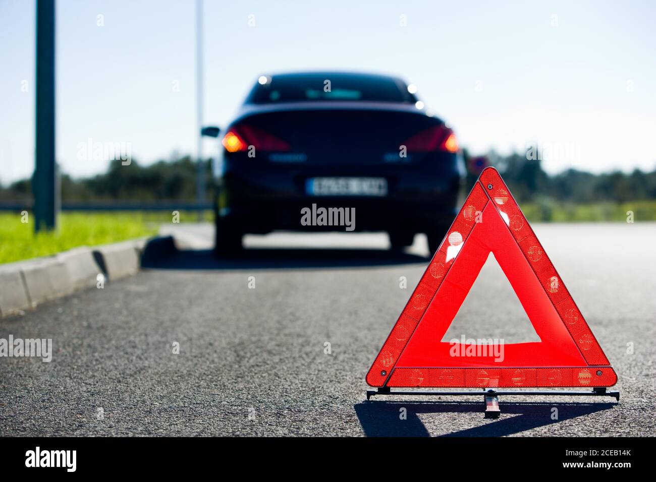 Warning red triangle sign on highway pavement with car on background ...