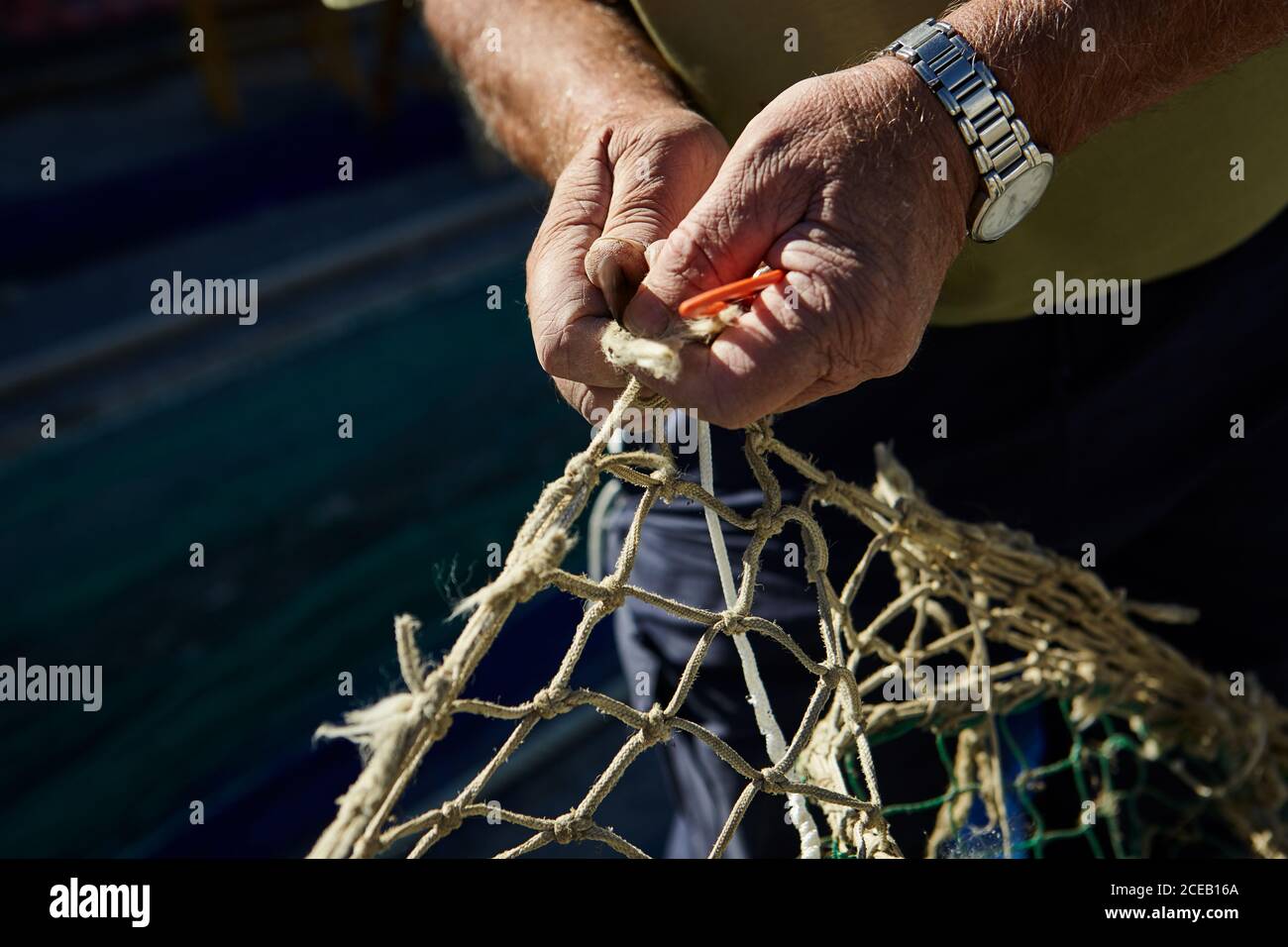 Crop from above view of man holding fishing net in hands and cutting ...