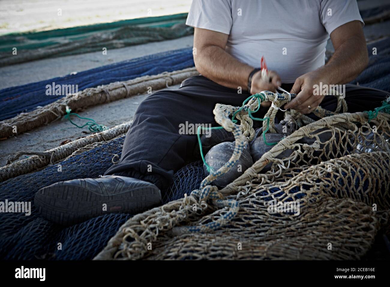 Crop from above view of man holding fishing net in hands and cutting ...