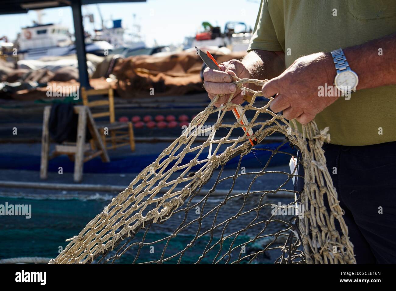 Crop from above view of man holding fishing net in hands and cutting ...