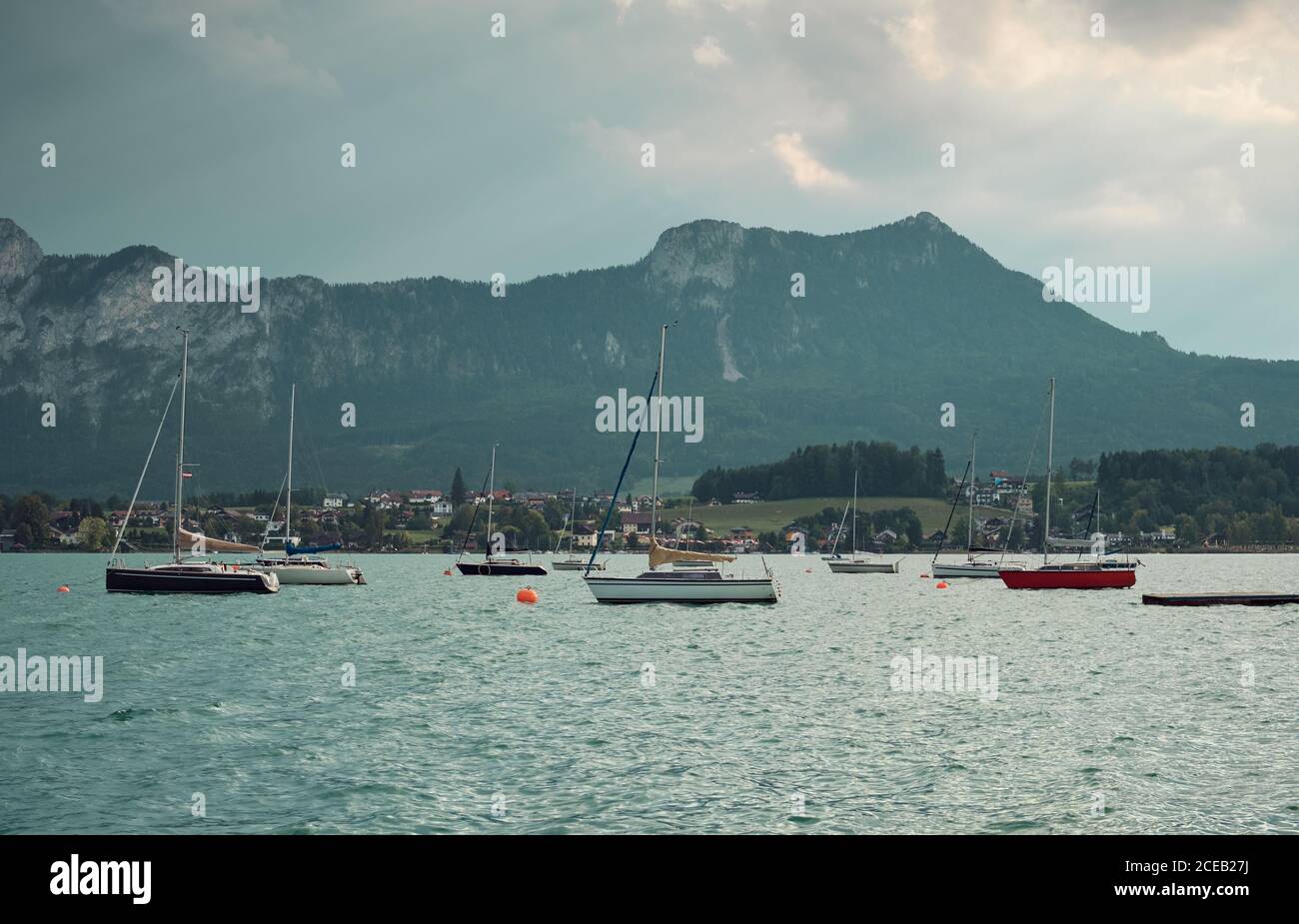 Side view of sailing scows floating on water along village's shore near ...