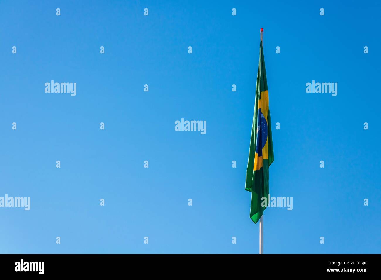 Concept image of a brazilian flag on pole without wind in front of blue ...