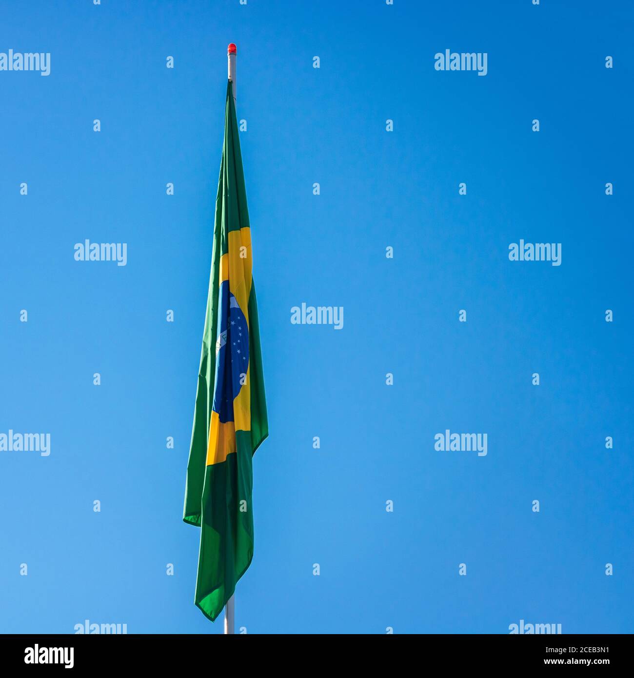 Concept image of a brazilian flag on pole without wind in front of blue ...