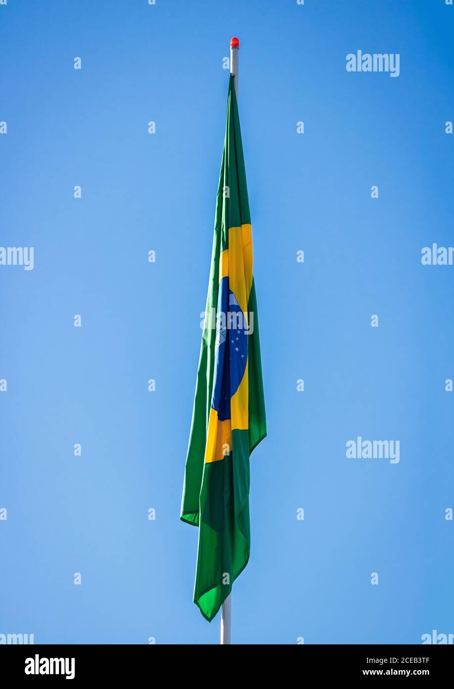 Concept image of a brazilian flag on pole without wind in front of blue ...
