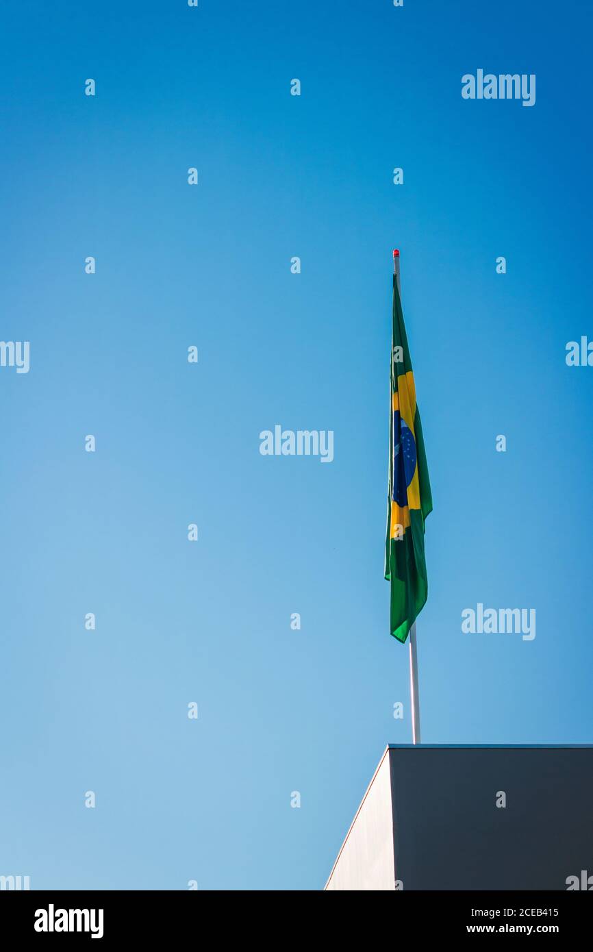 Concept image of a brazilian flag on pole without wind in front of blue ...