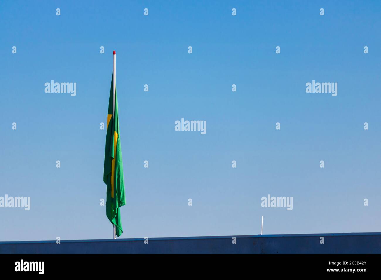 Concept image of a brazilian flag on pole without wind in front of blue ...