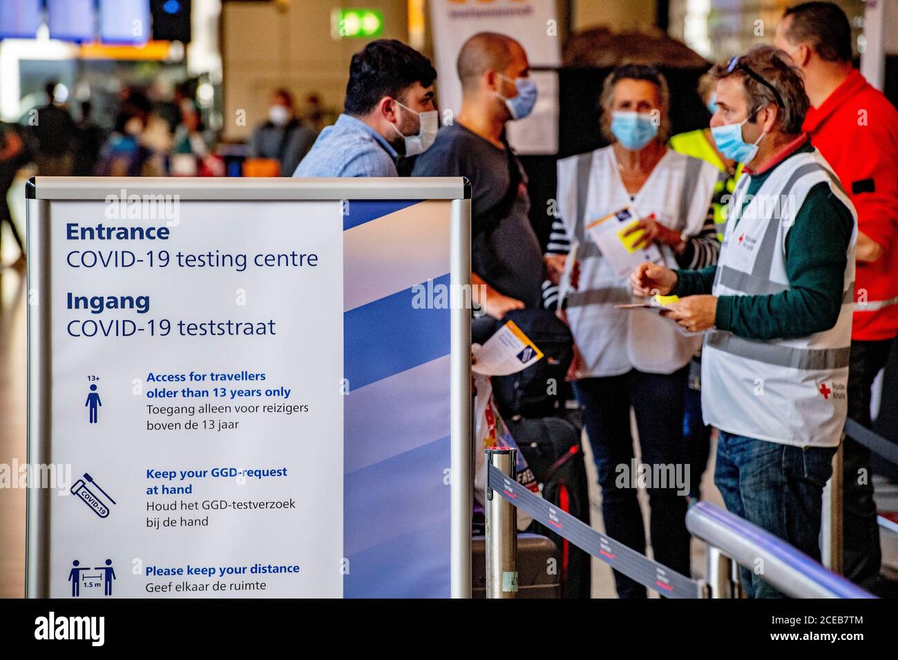 Travellers wear face masks as a preventive measure at Schiphol airport ...