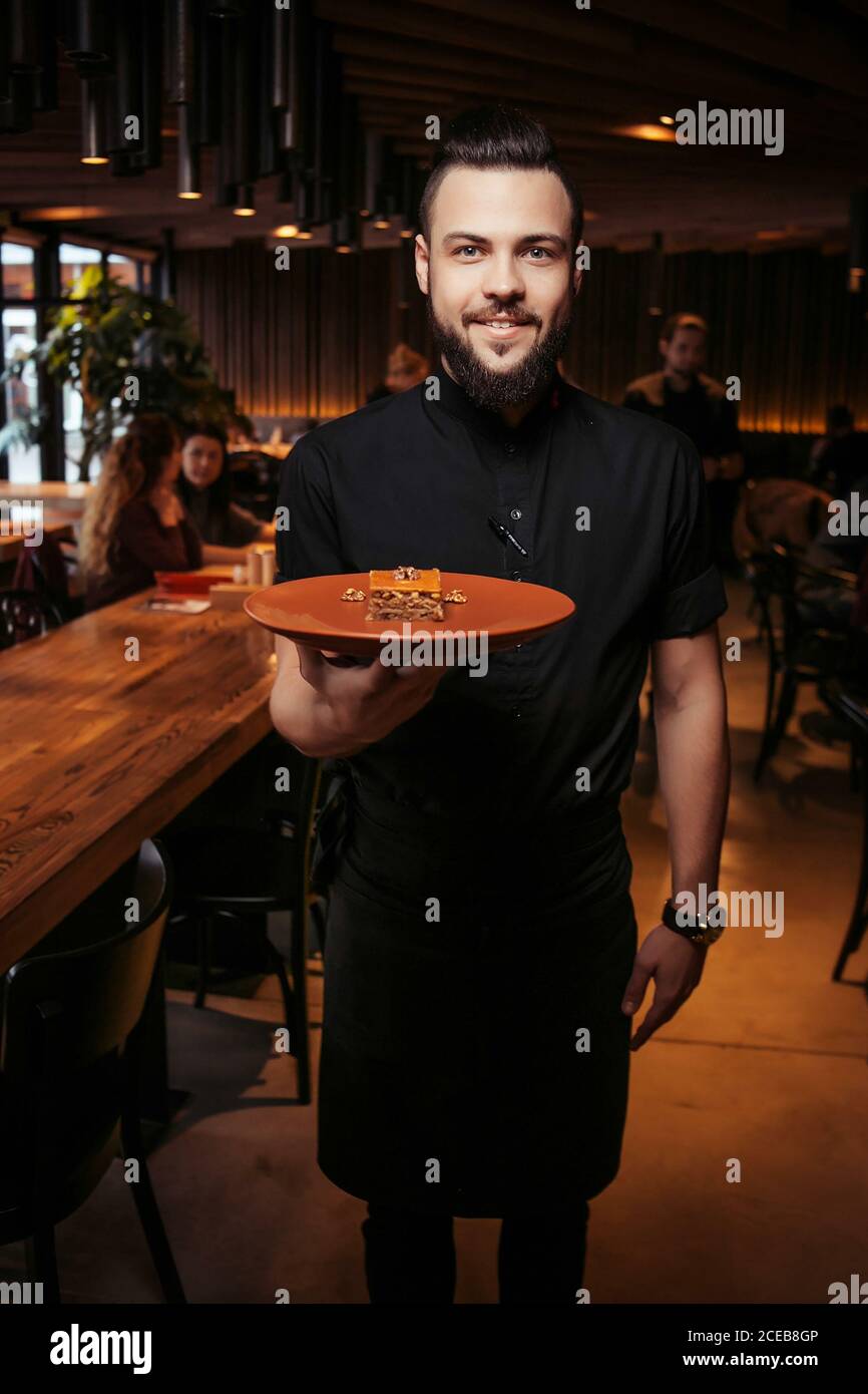 Cheerful bearded waiter with a slice of cake in a Georgian restaurant ...