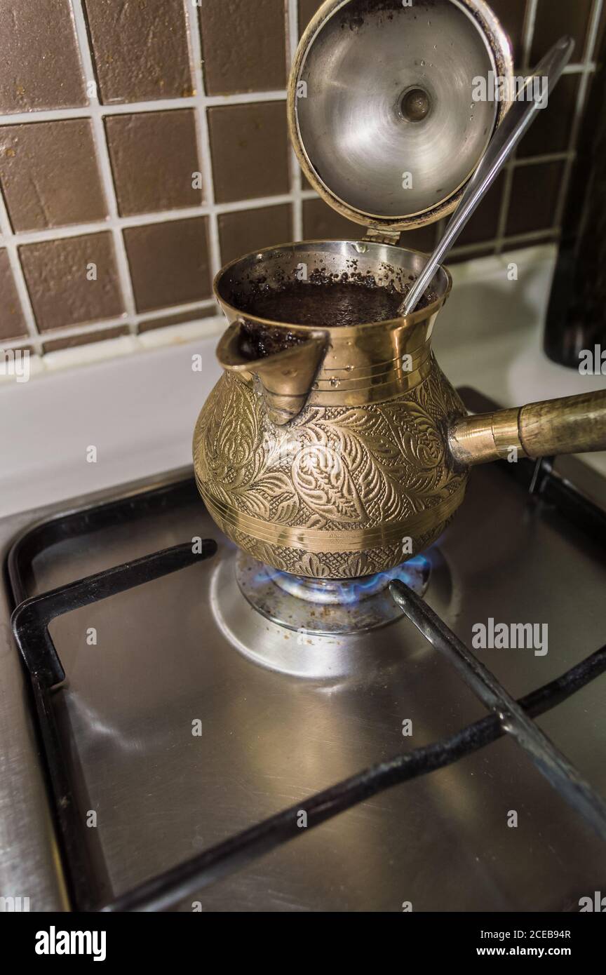 brewing fresh coffee in bronze turkish cezva on gas stove in the ...