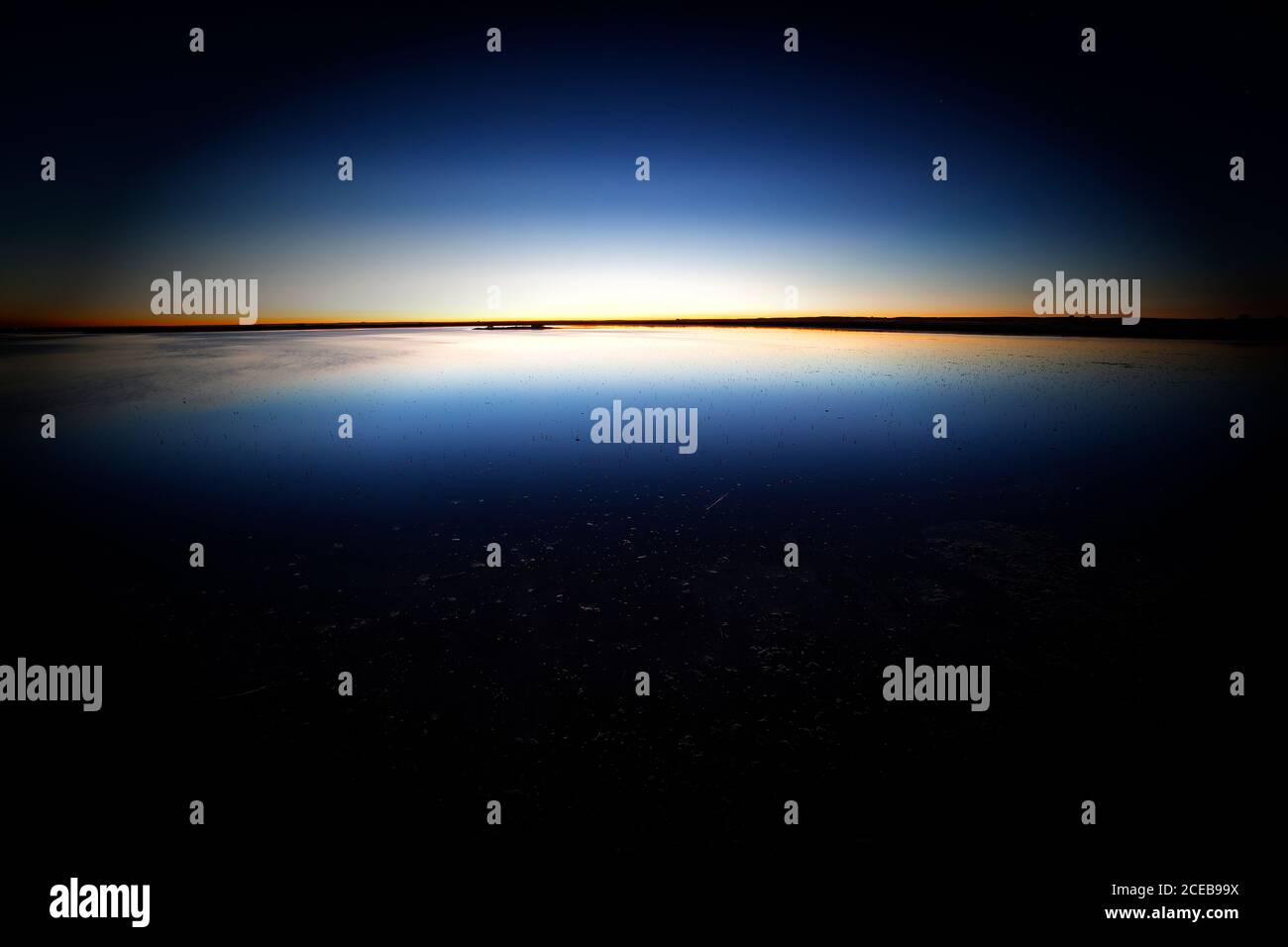 View of motionless water surface of lake in dark sunset light with ...