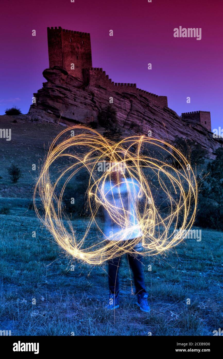 Blurred man waving hands with burning sparklers leaving golden traces ...