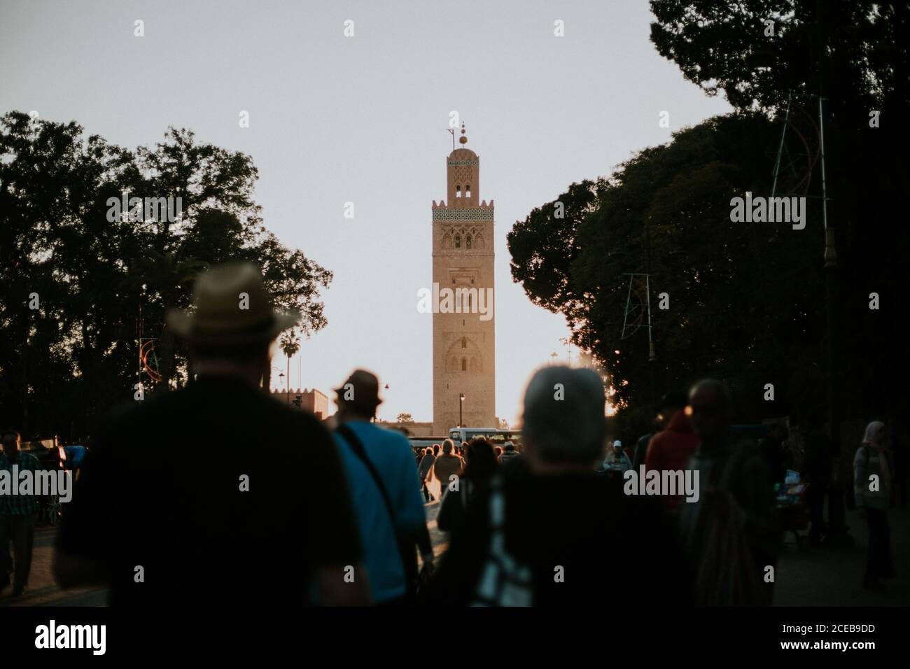 Back view of tourists looking at tall tower landmark in Morocco Stock ...