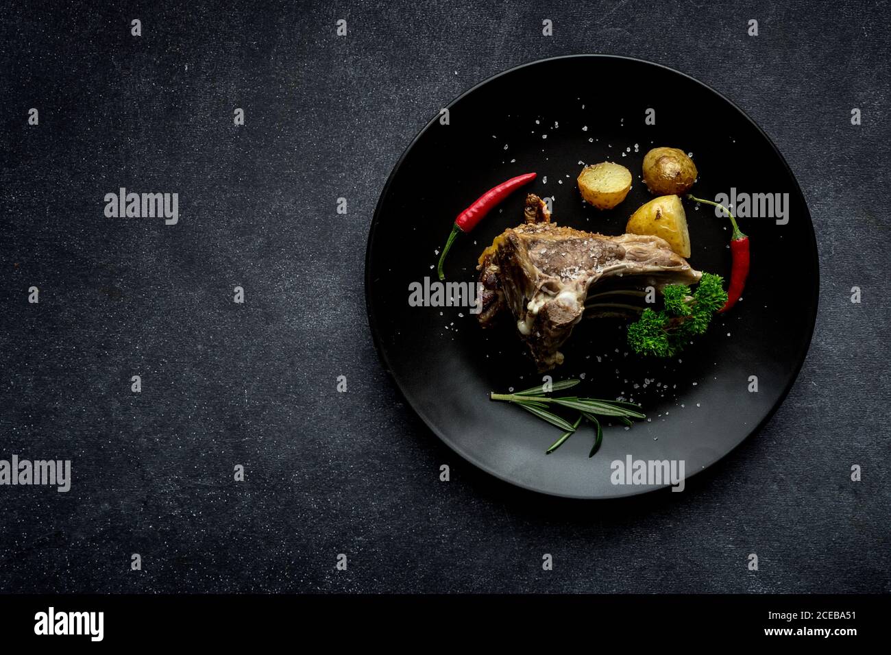 From Above a roast lamb on black plate Stock Photo - Alamy