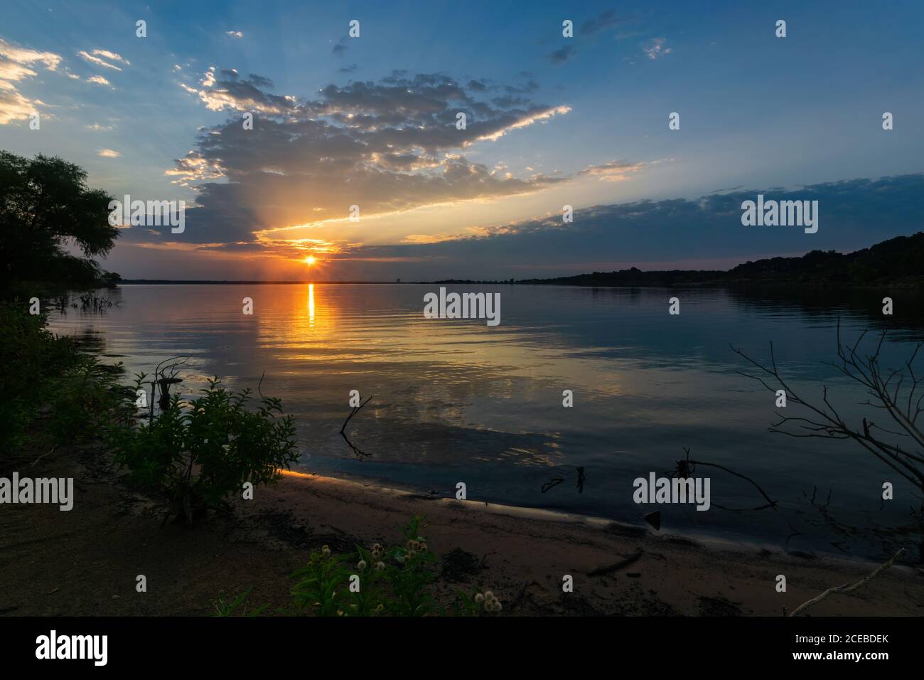 Sun and rays of sunlight peeking out from below clouds at sunrise on a ...