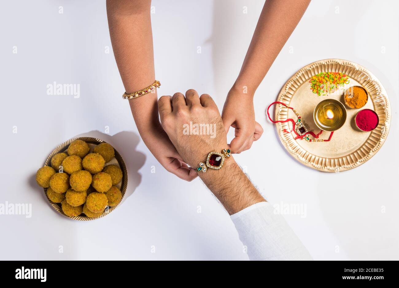 Close up top view of female hands tying colorful rakhi on her brother’s ...