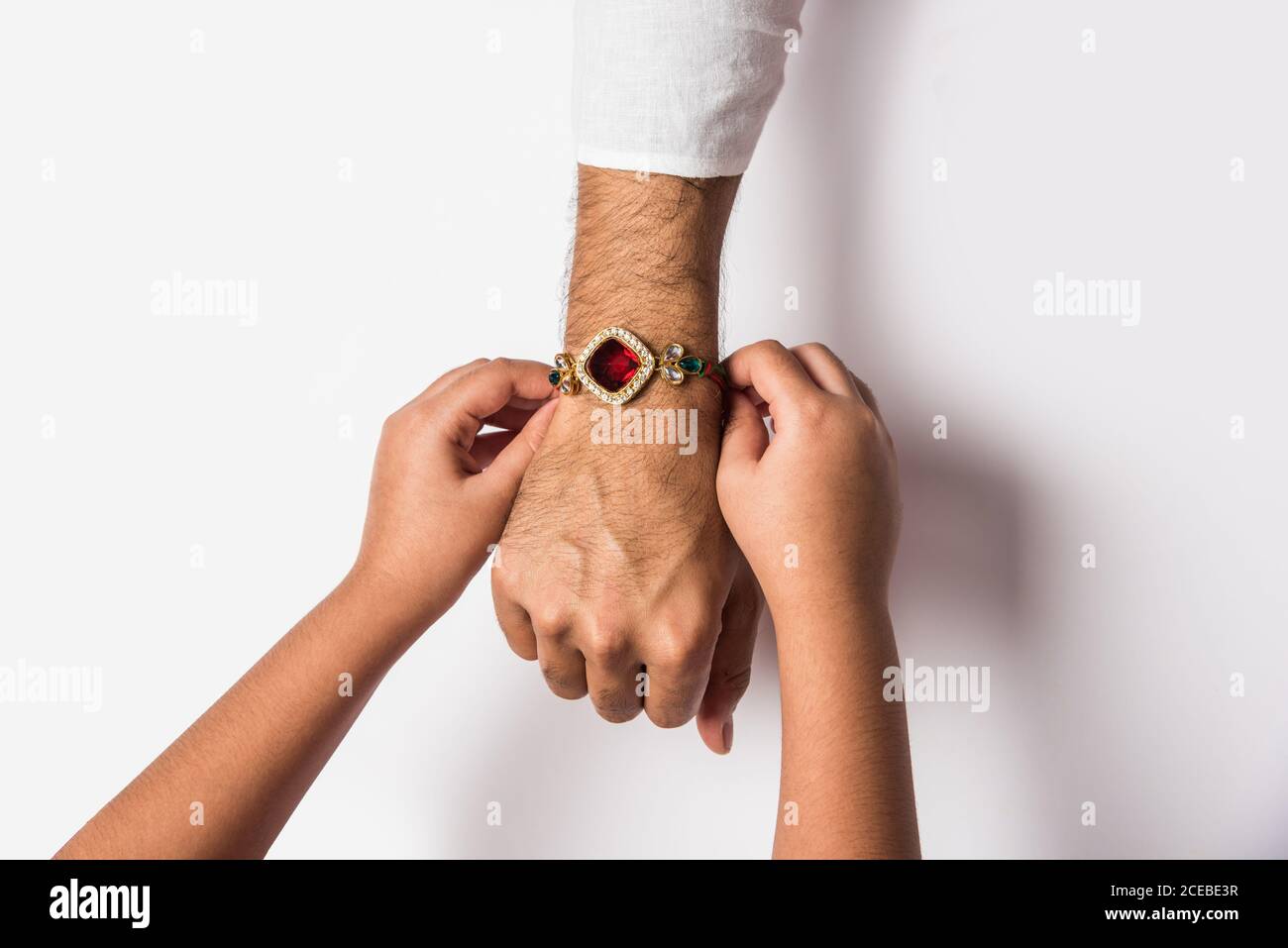 Close up top view of female hands tying colorful rakhi on her brother’s ...