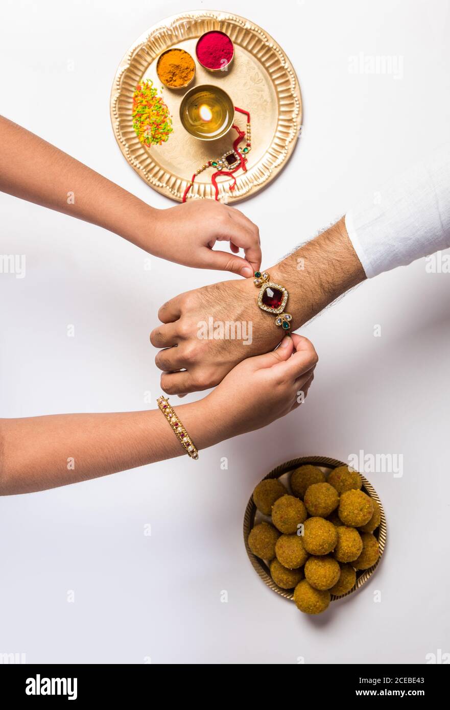 Close up top view of female hands tying colorful rakhi on her brother’s ...