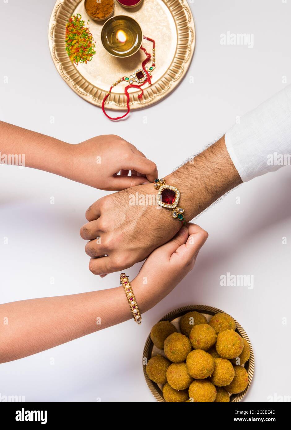 Close up top view of female hands tying colorful rakhi on her brother’s ...
