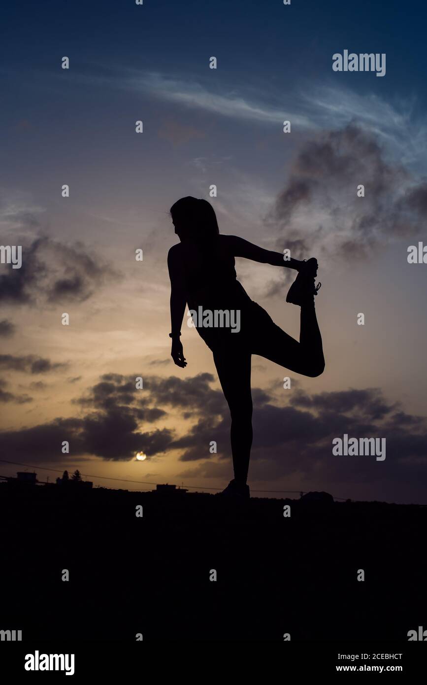 Stretching Woman and sky with clouds at sunset Stock Photo - Alamy