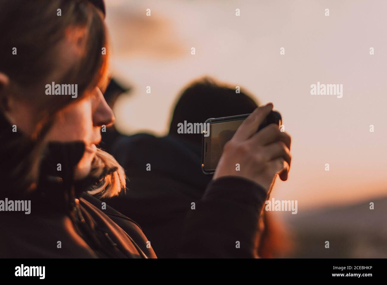 Woman shooting sunset on smartphone Stock Photo - Alamy