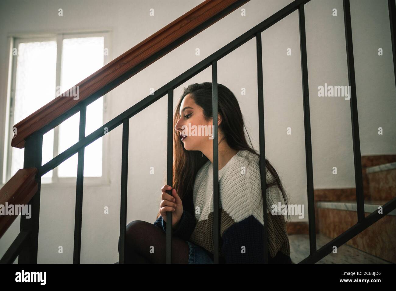 thoughtful teenage girl on the stairs of the interior of a building ...