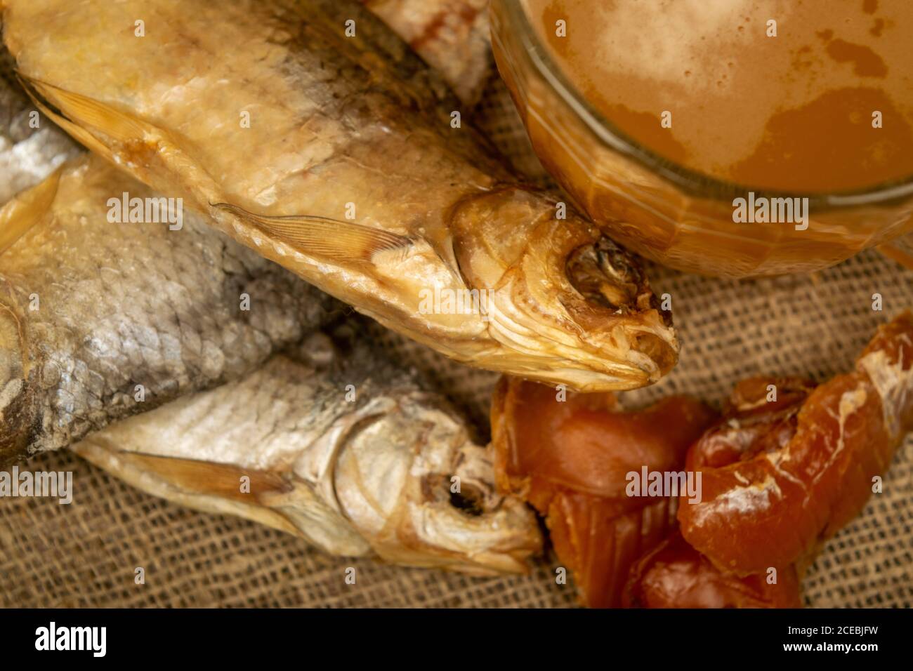 Dried fish, dried caviar and a beer mug on a homespun cloth with a ...
