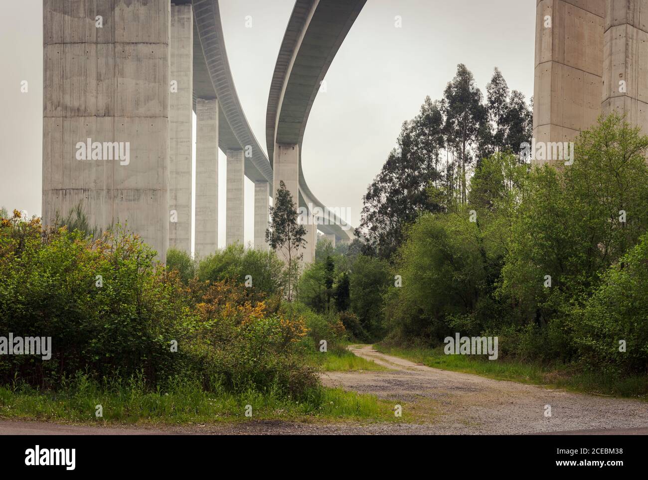 High viaduct made of white stone with green trees and bushes below and ...