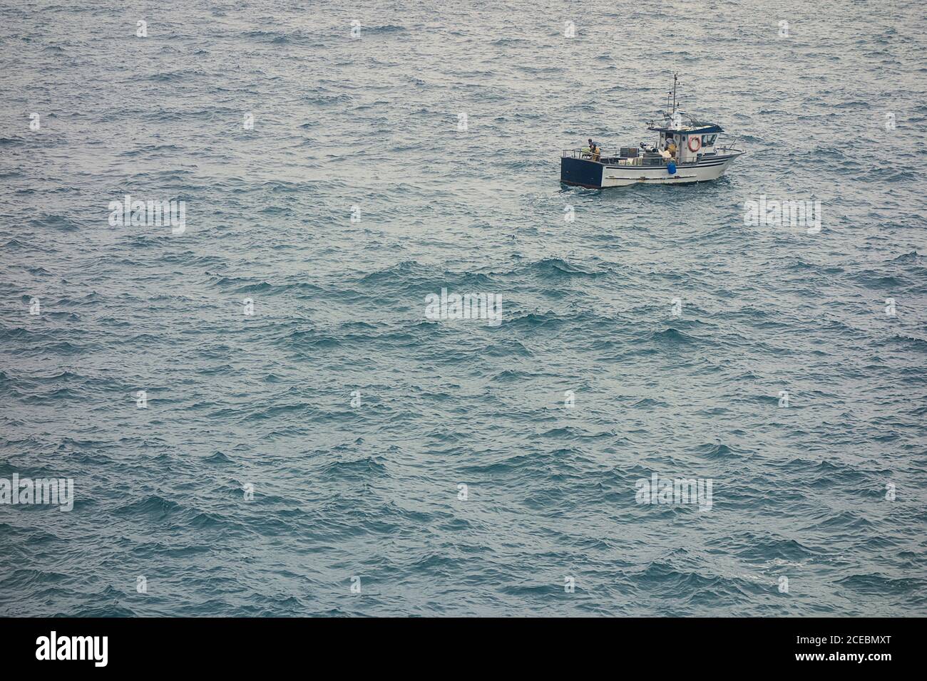 Aerial view of old small white fisher boat sailing in grey ocean water ...