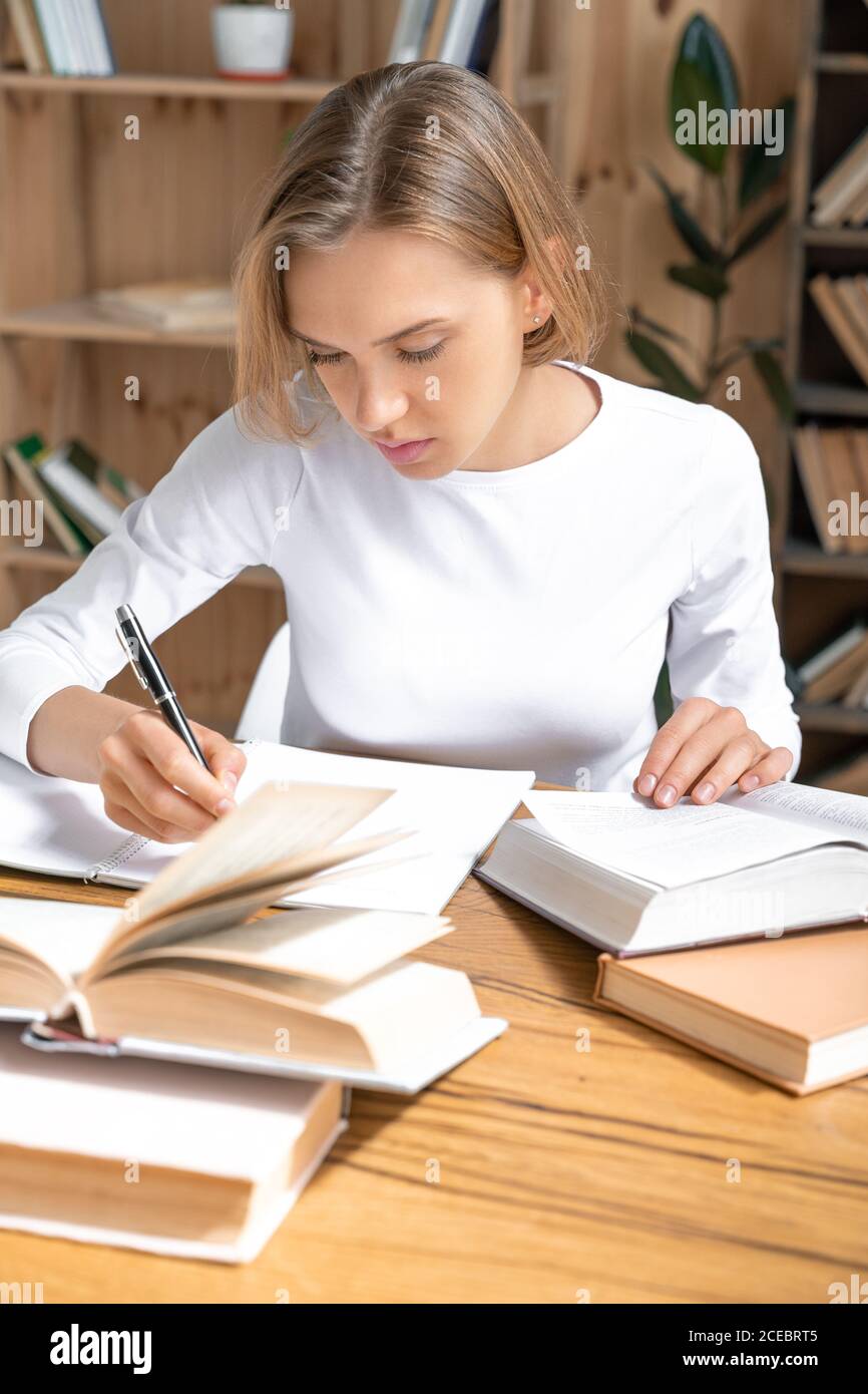 Concentrated young female student doing homework and preparing for ...