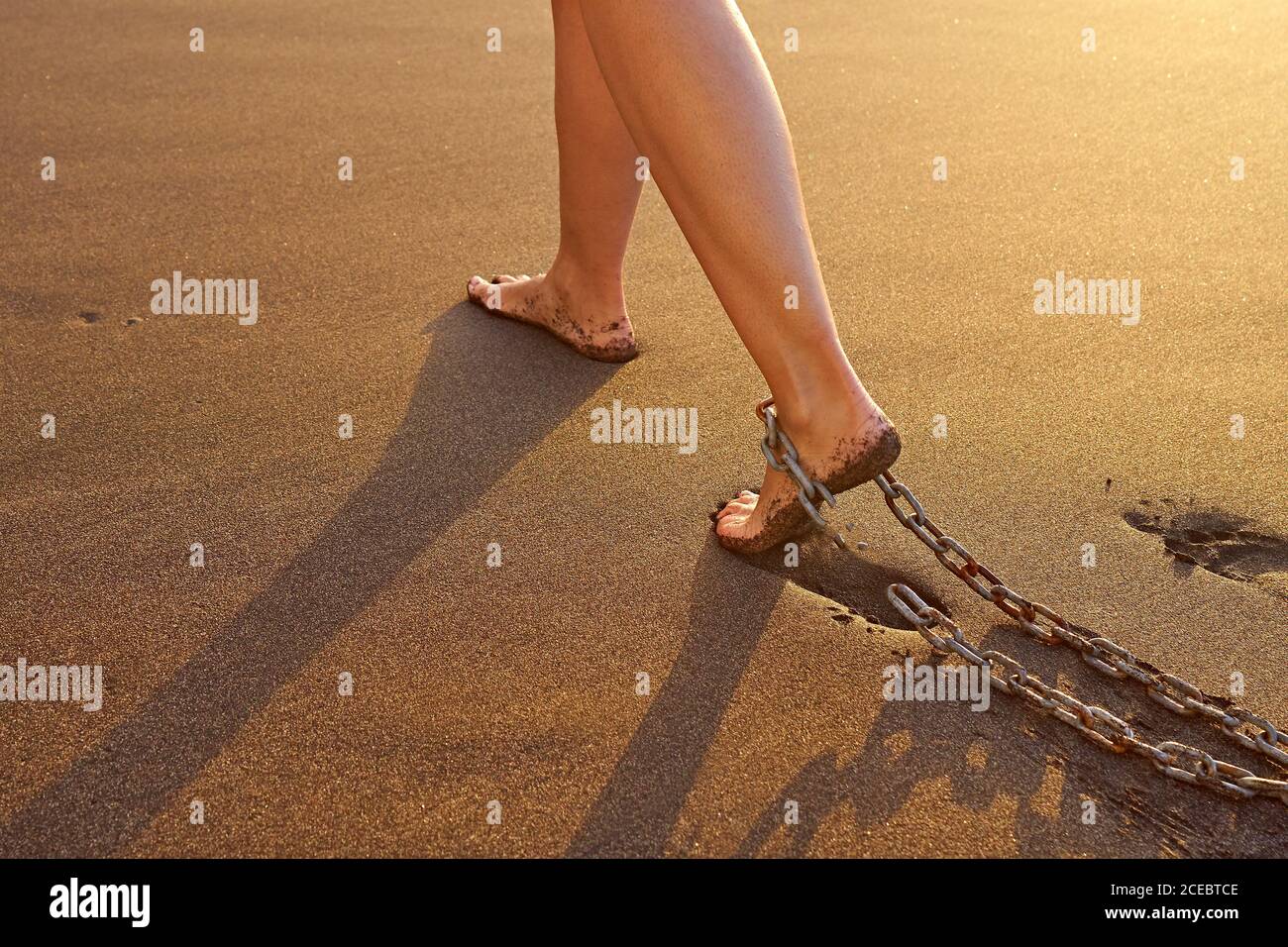 Crop view of barefoot Woman walking on smooth sandy beach with chain on ...