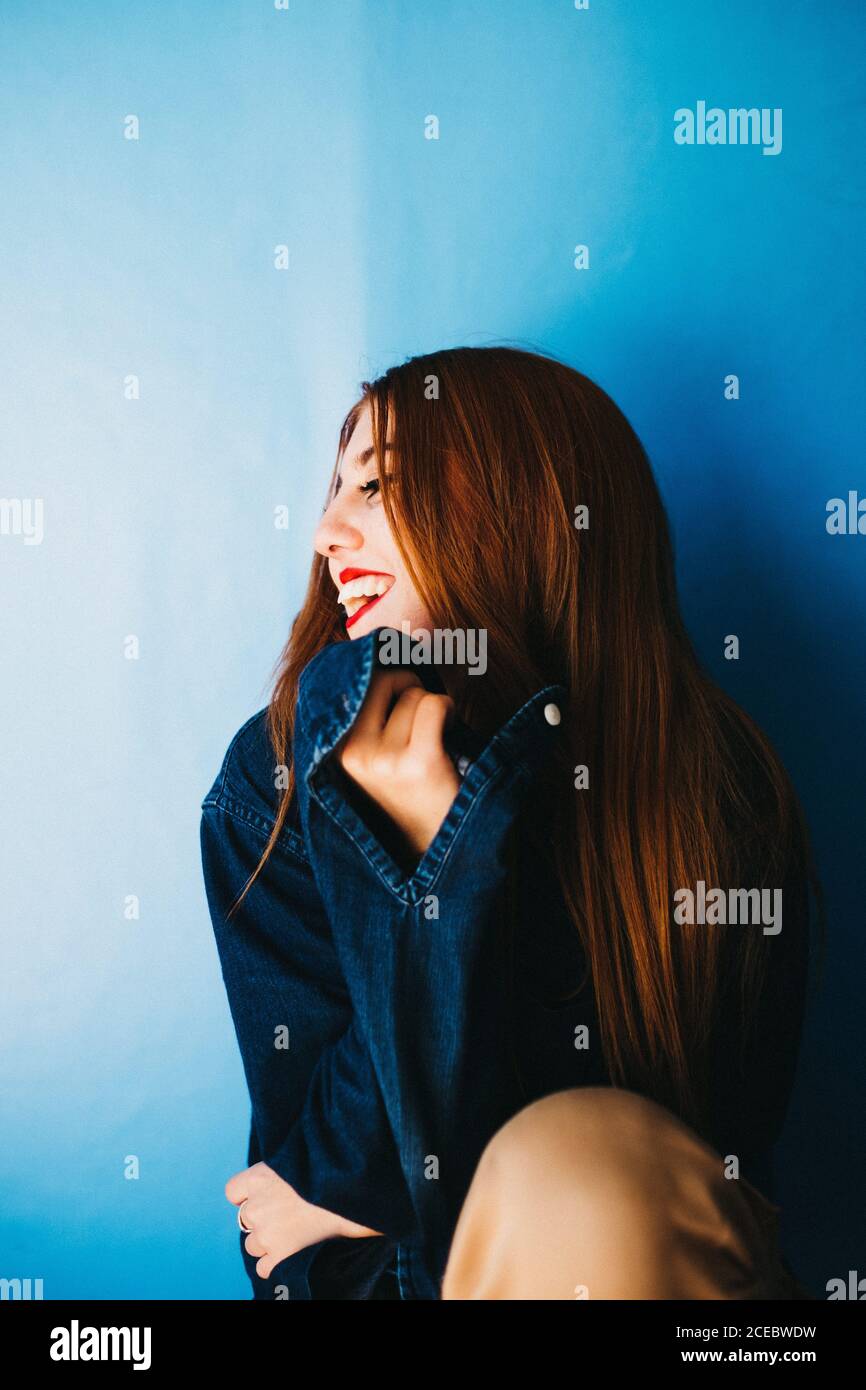 Attractive lady sitting near blue wall Stock Photo - Alamy