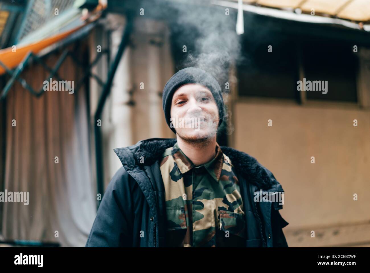 Handsome young man standing on street and having a smoke Stock Photo ...