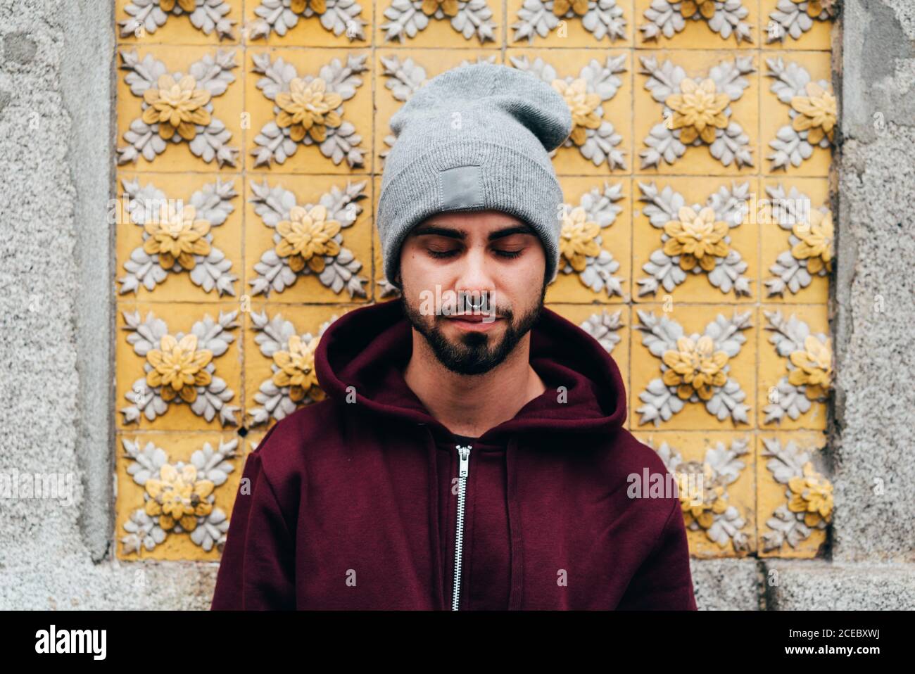 Handsome young man standing at wall with beautiful yellow tiles Stock ...