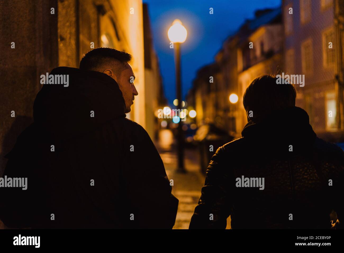 Back view of two men walking together on street at night Stock Photo ...
