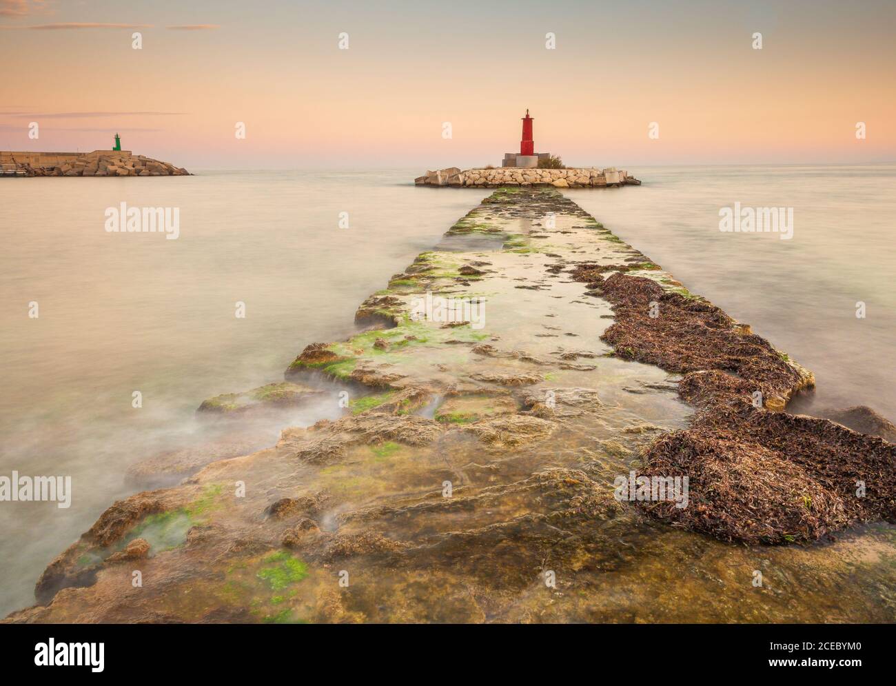 Rough path to islet with lighthouse Stock Photo - Alamy