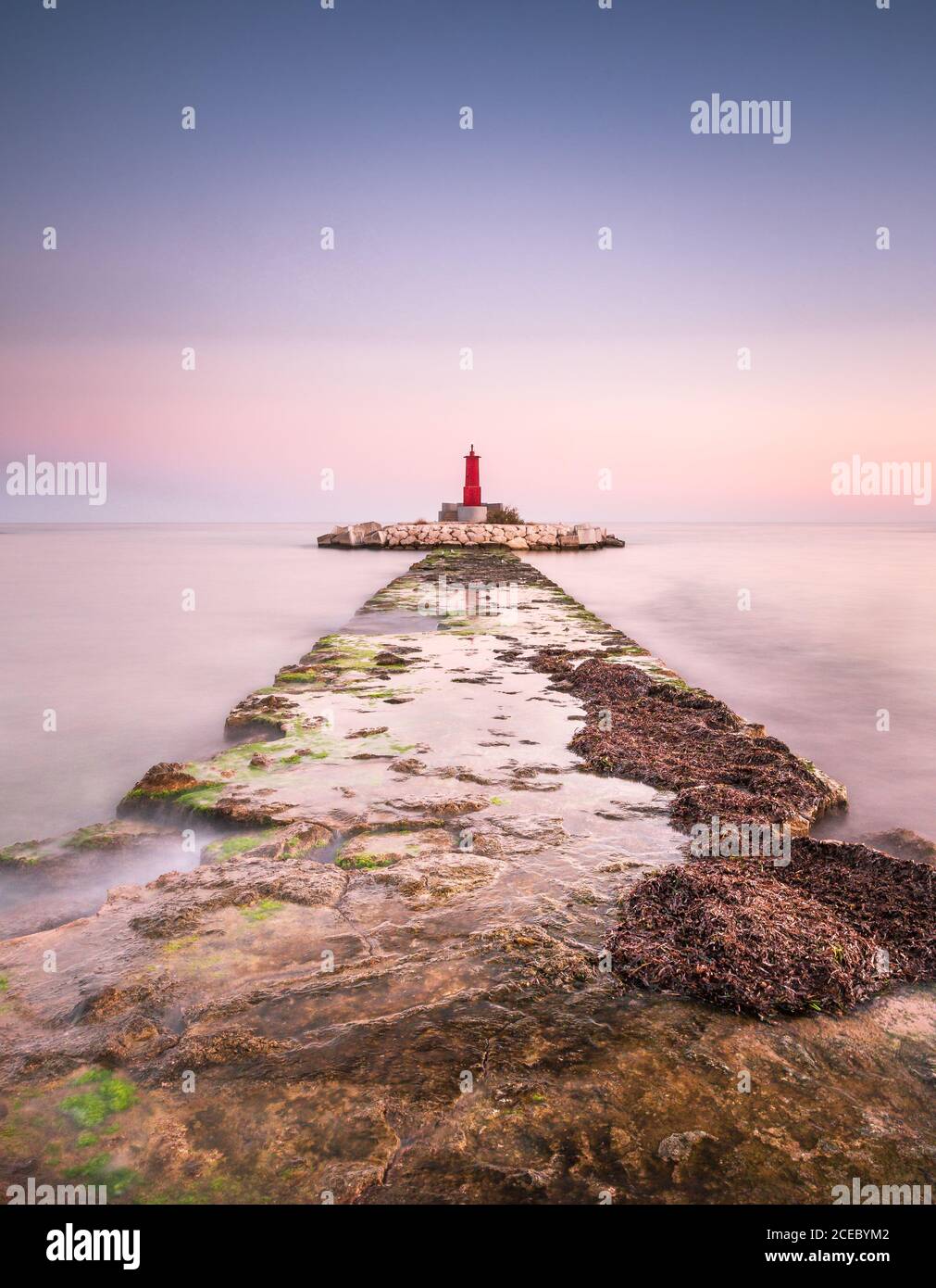 Rough path to islet with lighthouse Stock Photo - Alamy