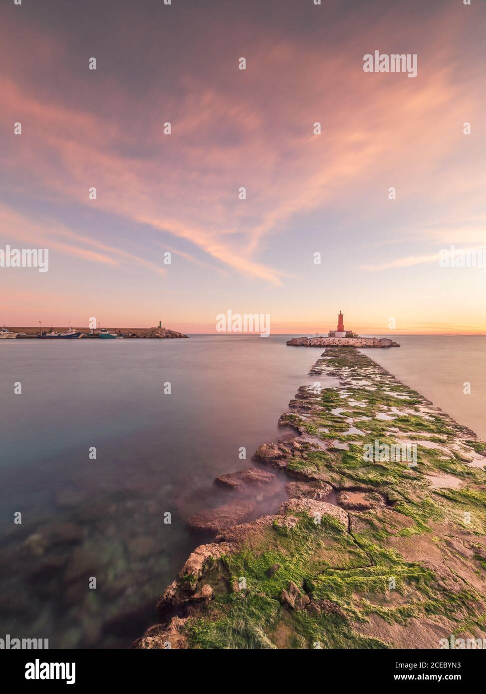 Rough path to islet with lighthouse Stock Photo - Alamy