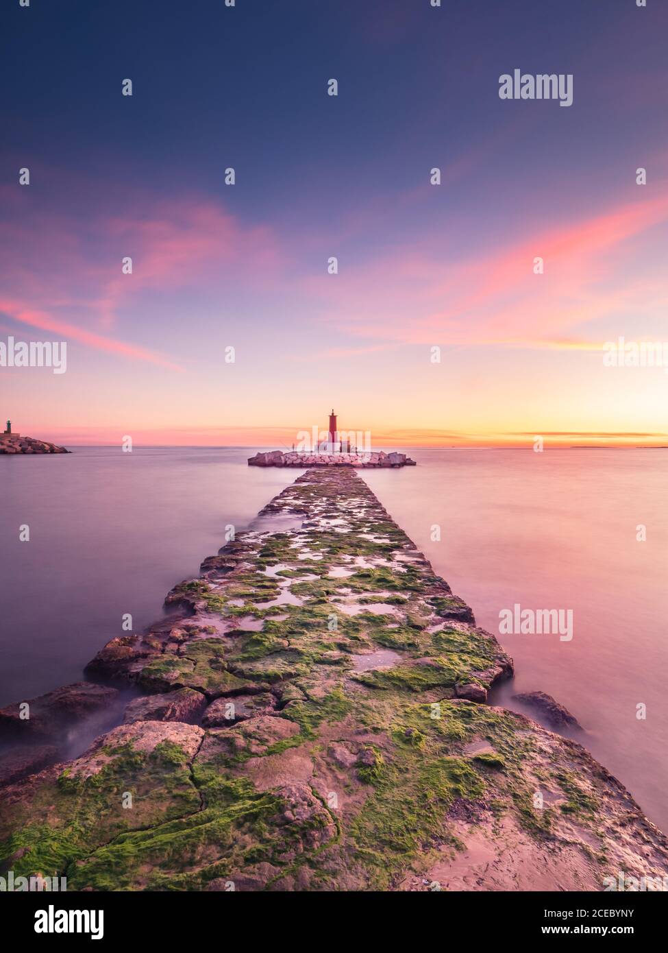 Rough path to islet with lighthouse Stock Photo - Alamy