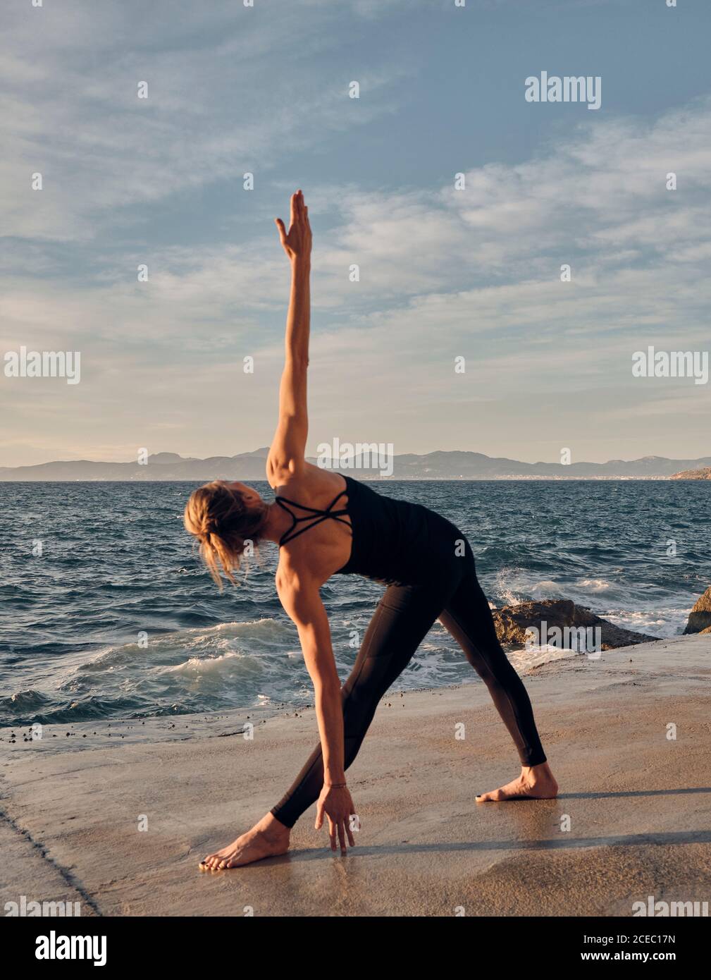 Young Woman standing in Triangle Pose near sea Stock Photo - Alamy