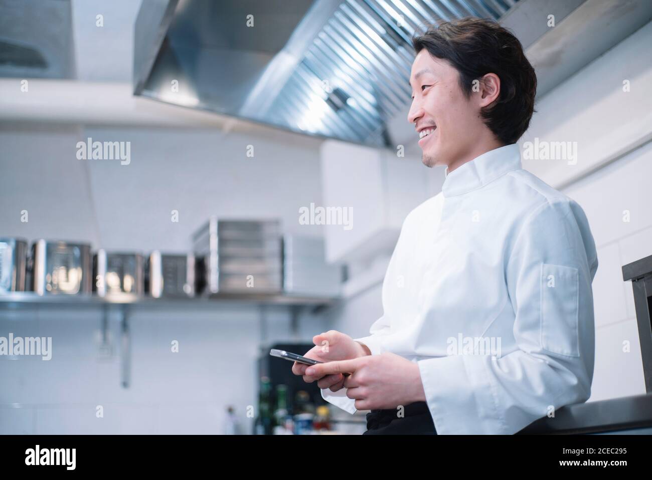 Side view of handsome Asian man in chef uniform standing in restaurant ...