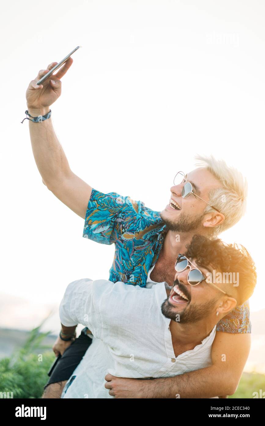 Handsome bearded guy giving piggyback ride to cheerful boyfriend and ...