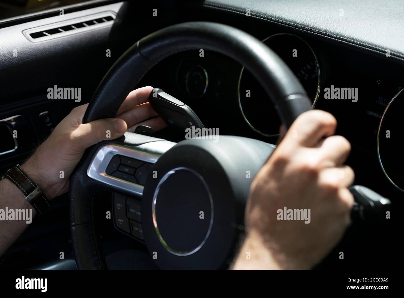 Crop shot of man driving modern car holding steering wheel and pushing ...